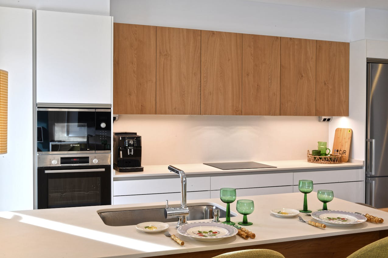 Cocina abierta con peninsula y mesa blanca y madera - CJR