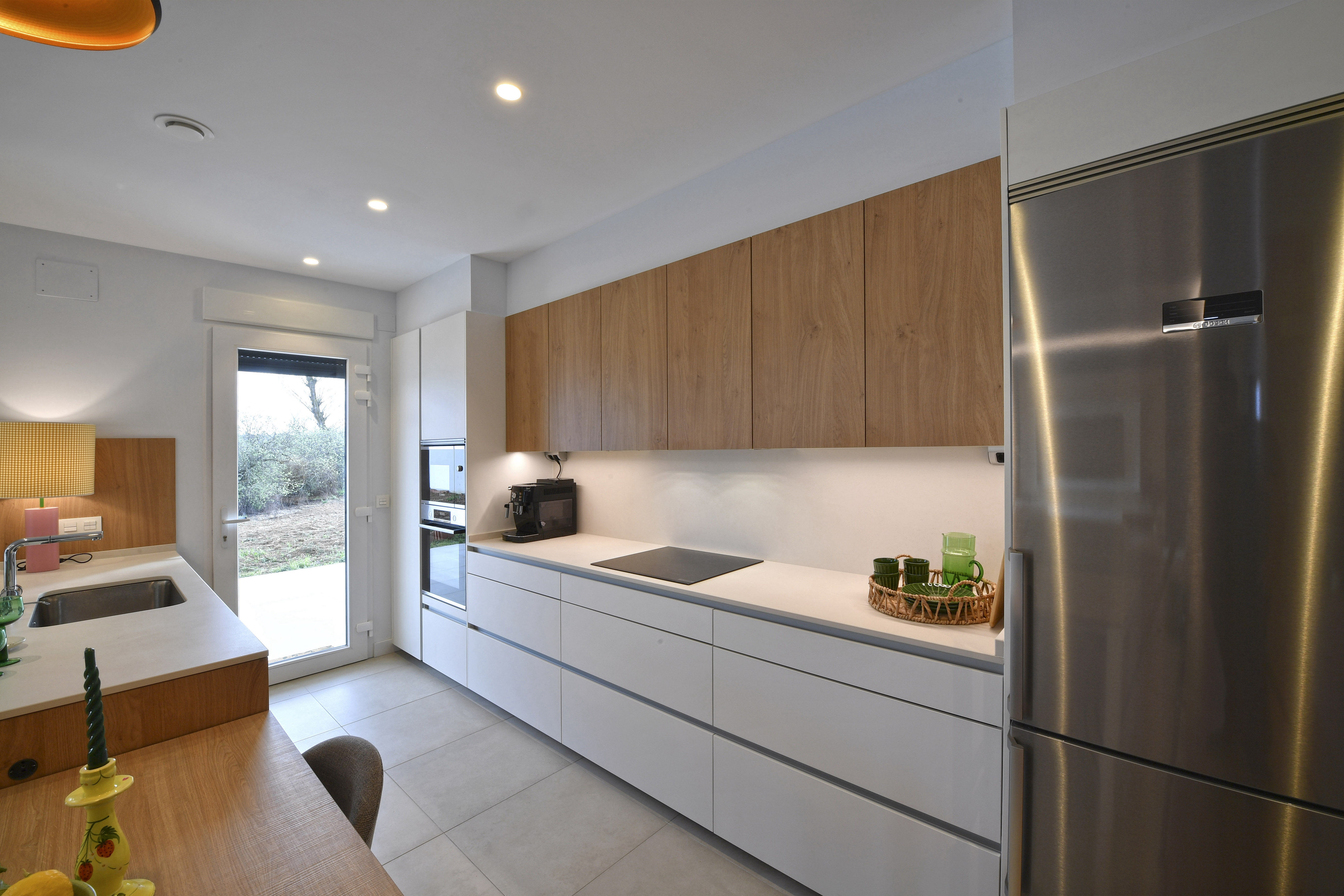 Cocina abierta con peninsula y mesa blanca y madera - CJR