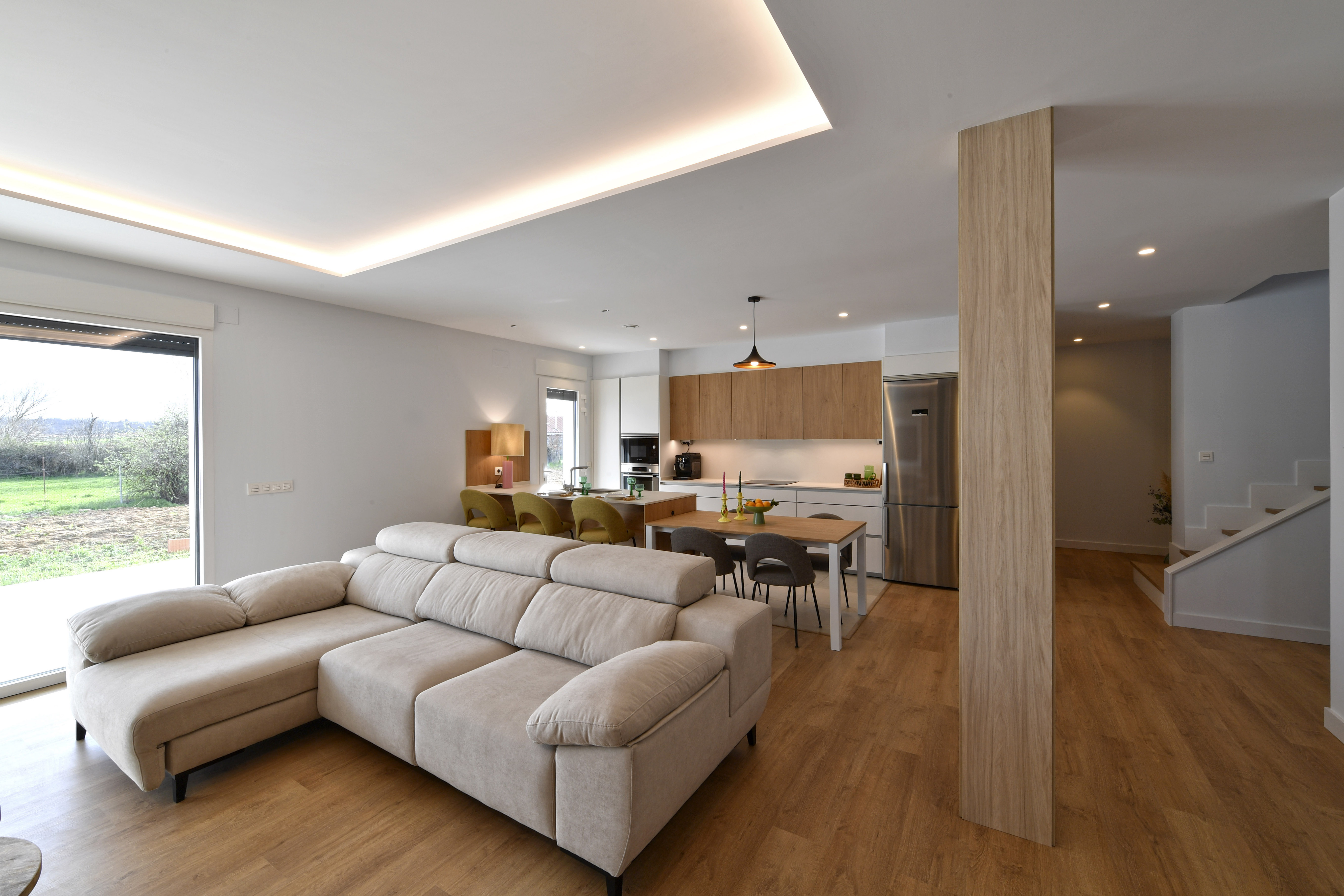 Cocina abierta con peninsula y mesa blanca y madera - CJR