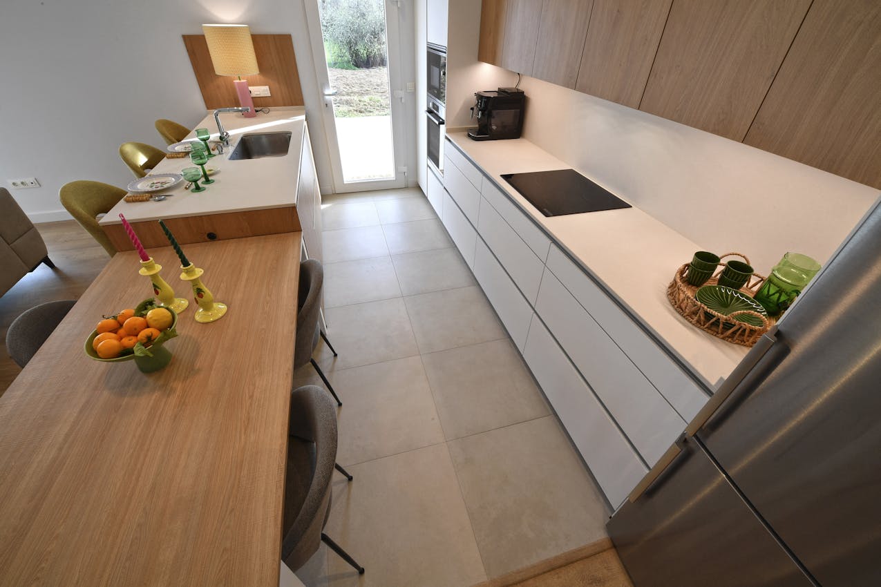 Cocina abierta con peninsula y mesa blanca y madera - CJR