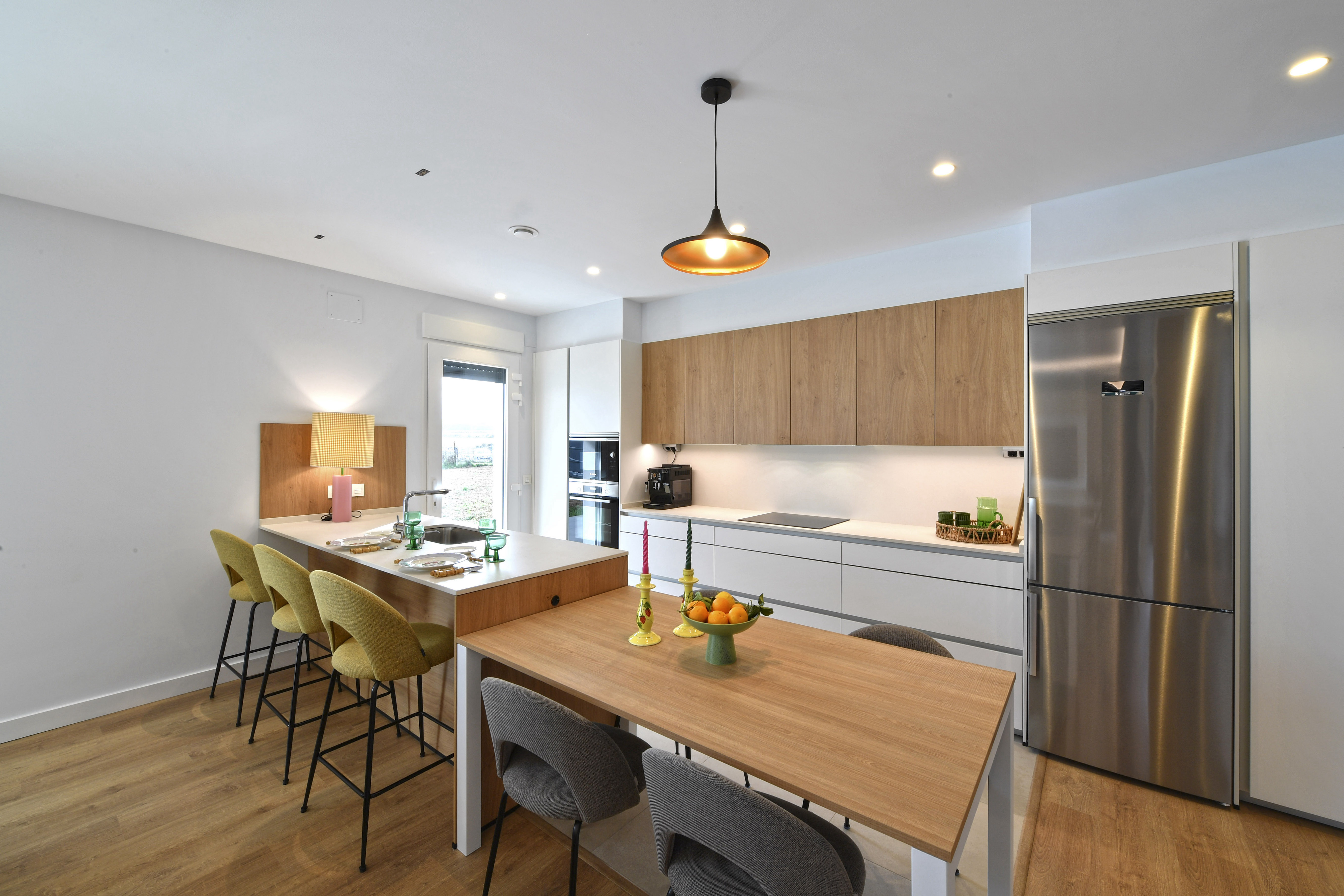 Cocina abierta con peninsula y mesa blanca y madera - CJR